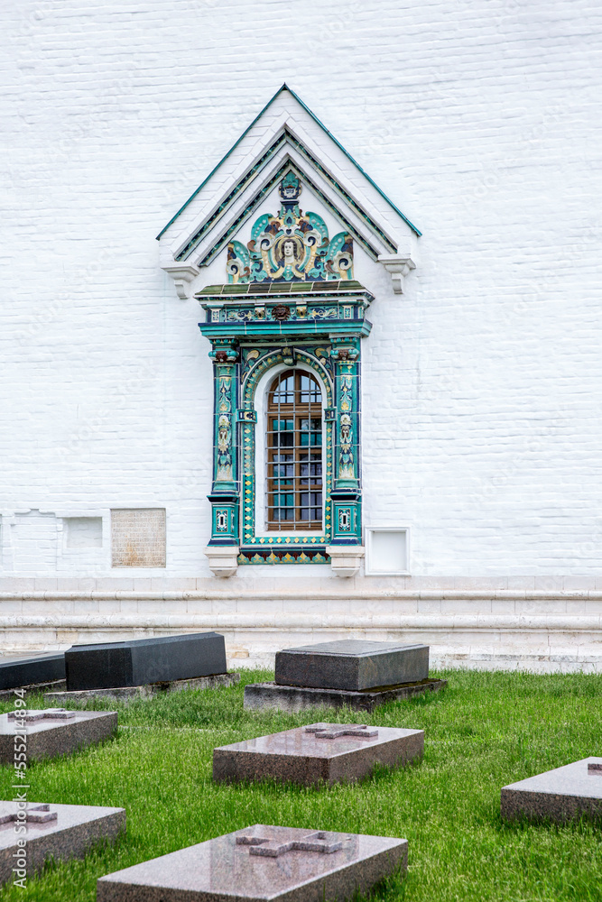 Marble tombstones on a green lawn in a cemetery near the white brick ...
