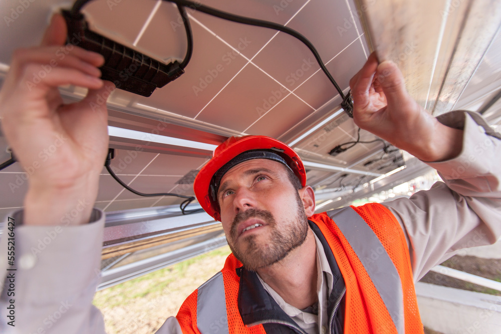 Solar photovoltaic installer working on power connections for a PV ...