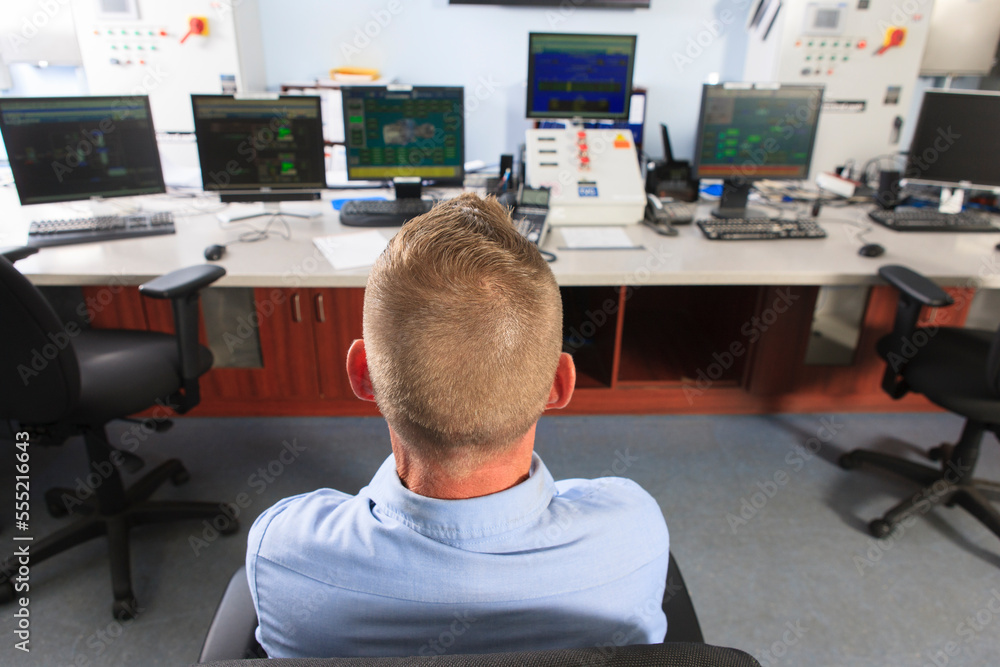 Engineer at electric power plant control room watching management ...