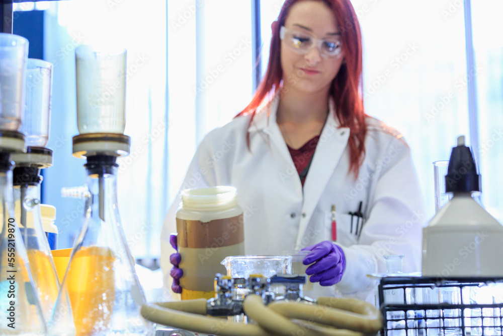 Lab assistant at water treatment plantLab chemist adding reagent to ...