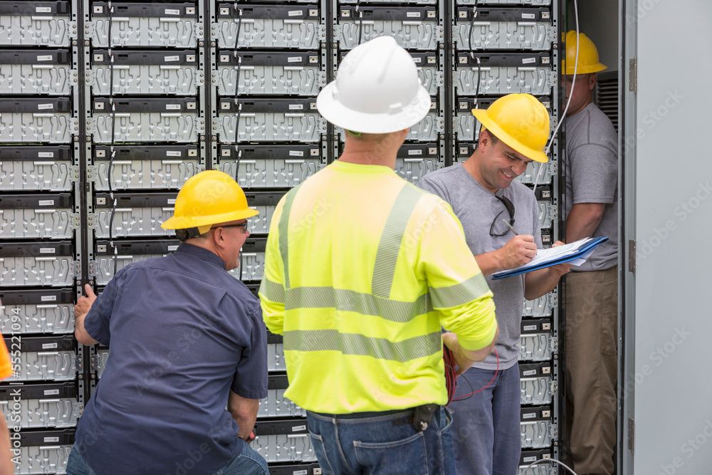 Engineers connecting energy storage batteries for back up power to an ...