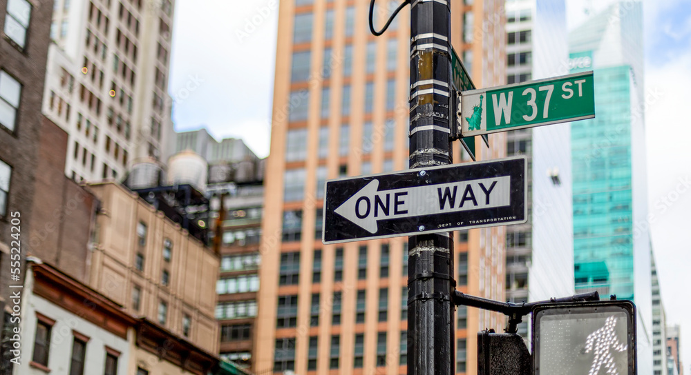 Street signs on a post, a directional one way, pedestrian walk signal ...