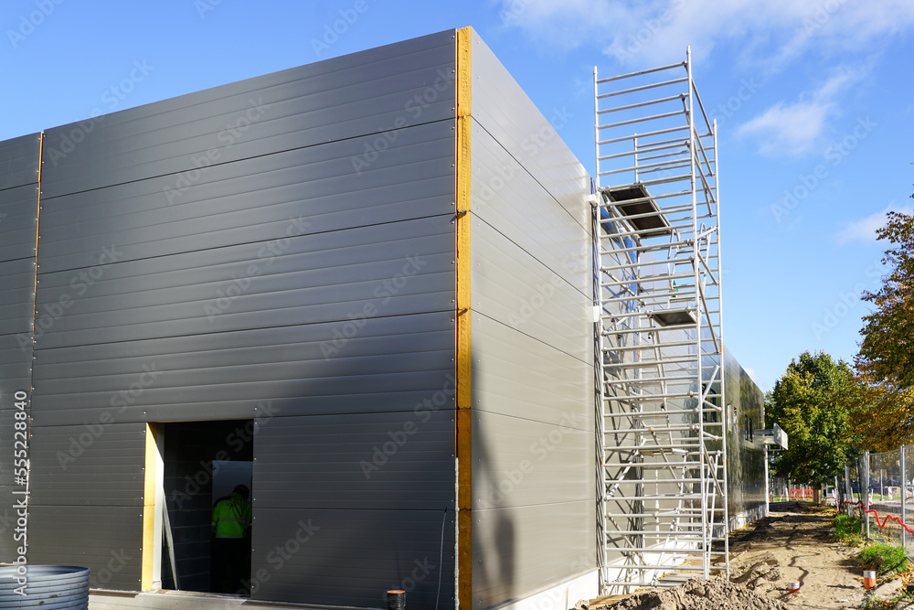 Gray sandwich panel facade of a unfinished warehouse building, tubular ...