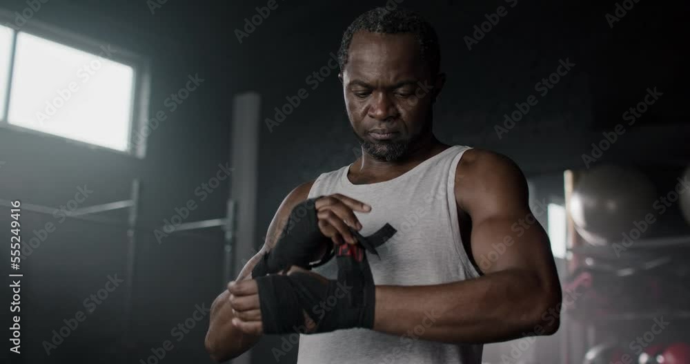 Portrait of serious angry bearded African man fighter wrapping wrists ...