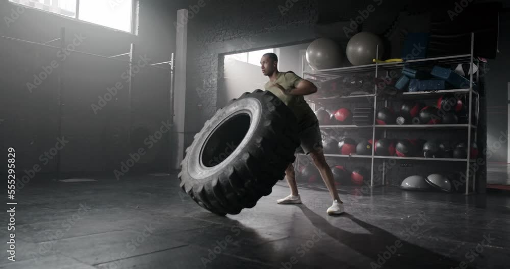 Handsome sporty muscular young man lifting heavy tire for crossfit ...