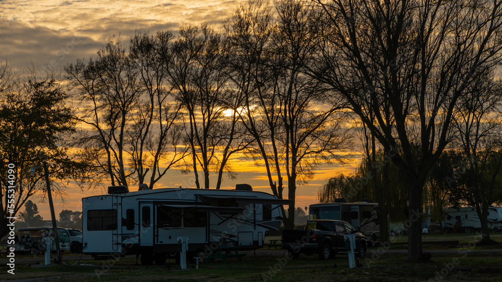Camping under sunset sky in a trailer with truck and motorhomes at campsite Stock 写真 | Adobe Stock