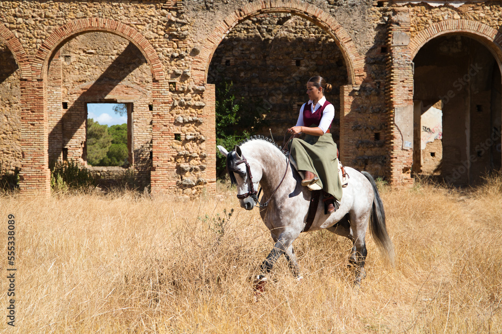 Young and beautiful Spanish woman on a Thoroughbred horse riding in the ...
