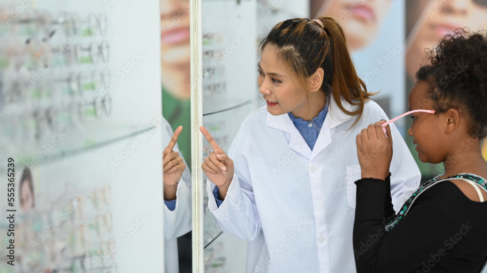 Optician helping African American girl choosing spectacles glasses. Eye ...