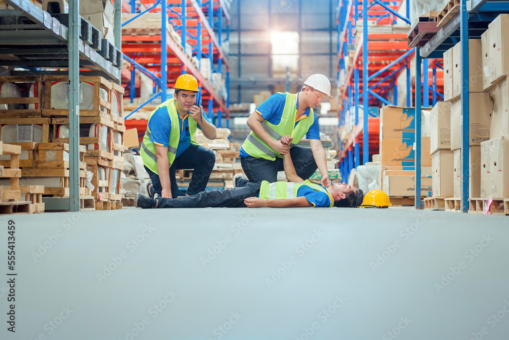 Panoramic Warehouse worker do first aid to his colleague lying down on ...