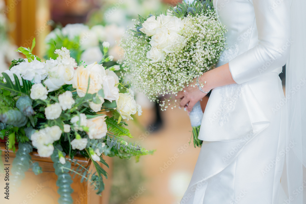 The bride dressed in white in the vast church attends the Christian ...