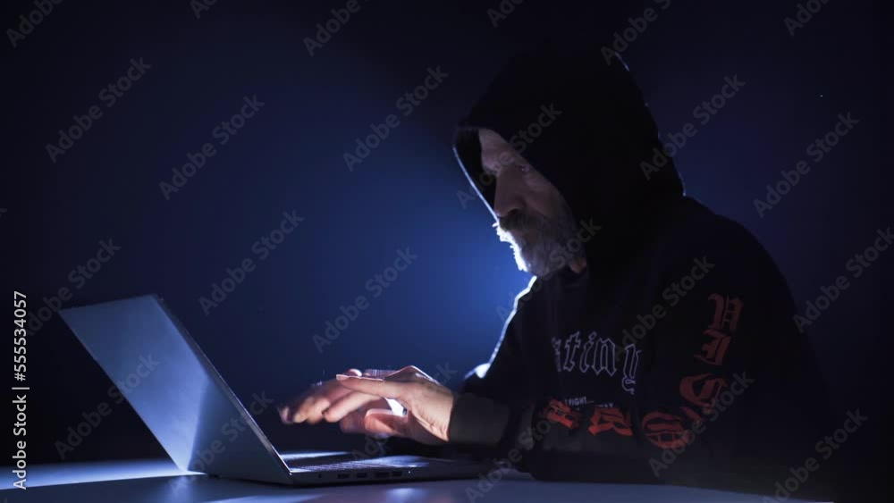Hacker male commit crime from laptop by cracking password. Hacker man starts typing on laptop ...