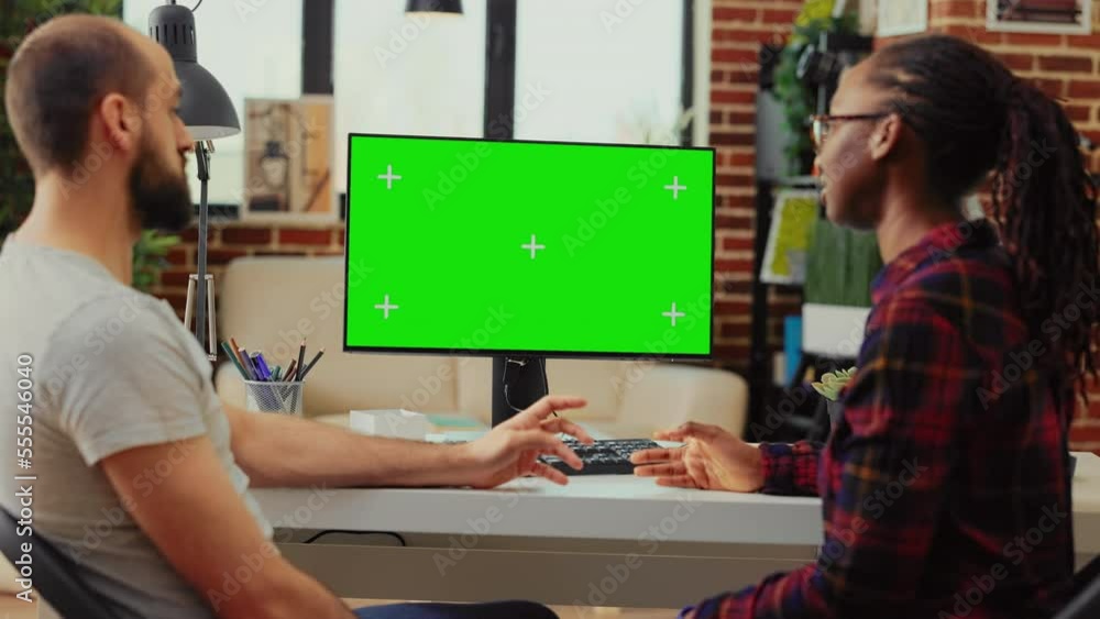 Diverse team working on computer with greenscreen at desk, using ...