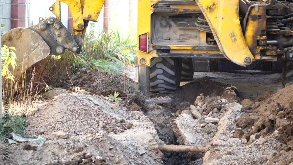 Excavator digs a trench to lay pipes. Close up of an excavator digging ...