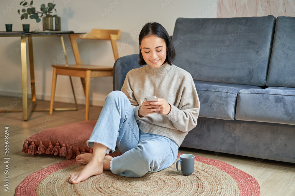 Image of stylish young woman in modern house, using mobile phone ...