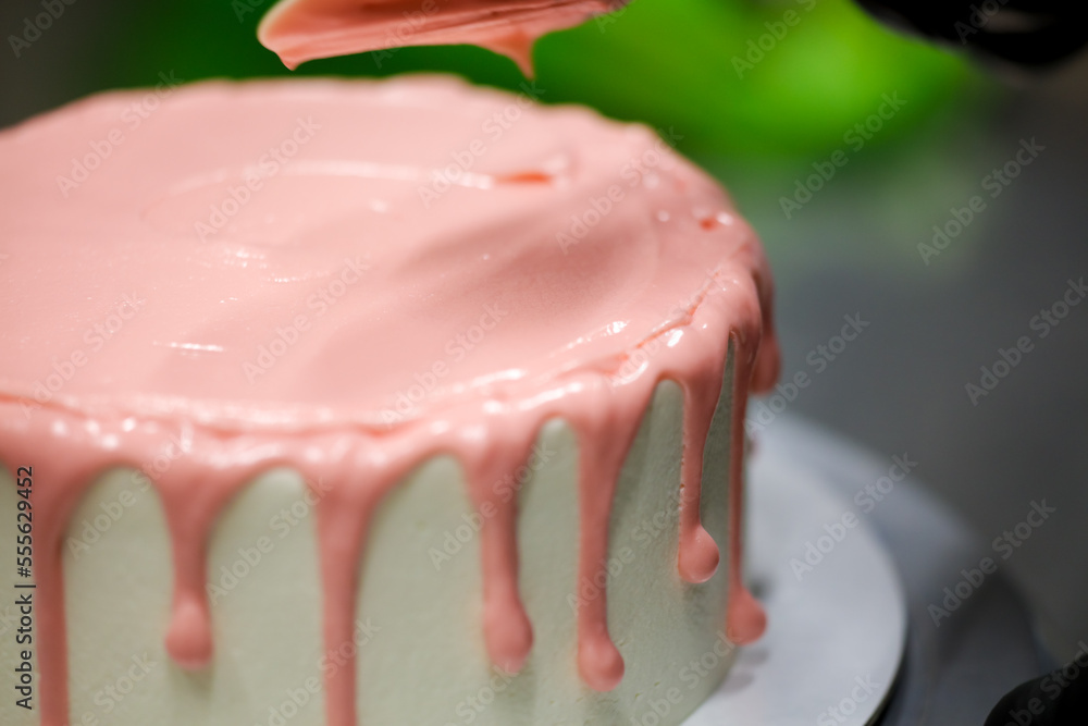 pastry chef making a pink dripping frosted cake for baby girl birthday ...