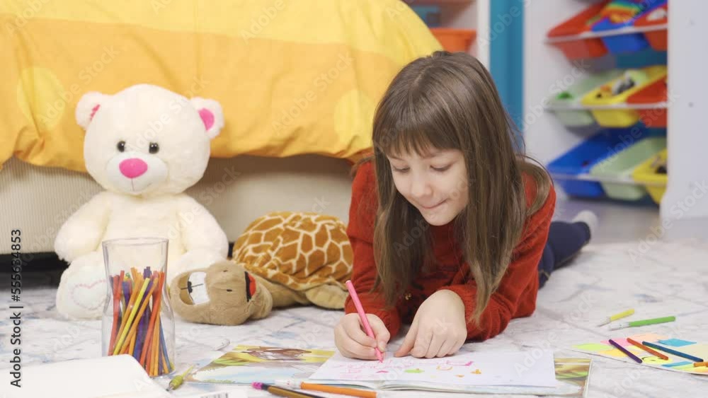 Creative and dreamy little girl draws with colored crayons in her room ...