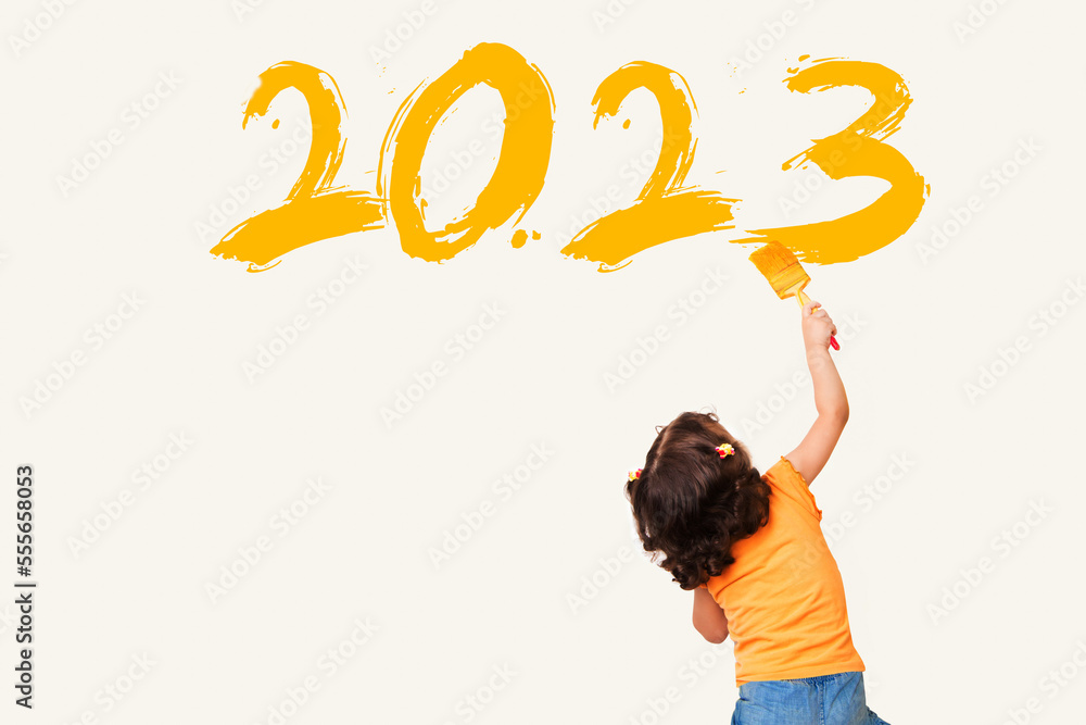 Cute little girl drawing new year 2023 with painting brush on wall ...
