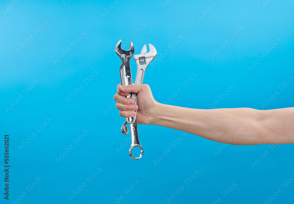 Human hand holding wrenches on blue background Stock Photo | Adobe Stock