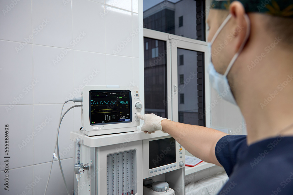 Anesthesiologist regulates anesthesia apparatus for patient with his ...