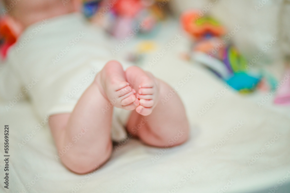 Crossed legs of the baby on a white background. A little girl lies on a ...