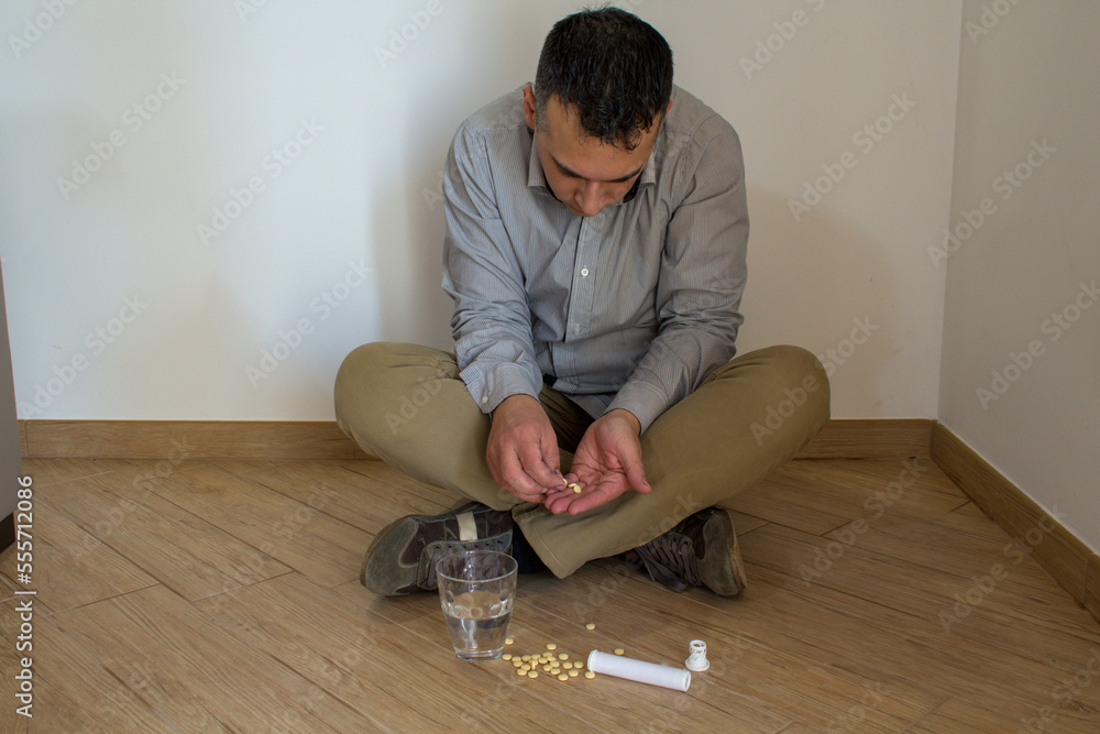 Image of a desperate man sitting on the ground abusing pills. Drug and ...