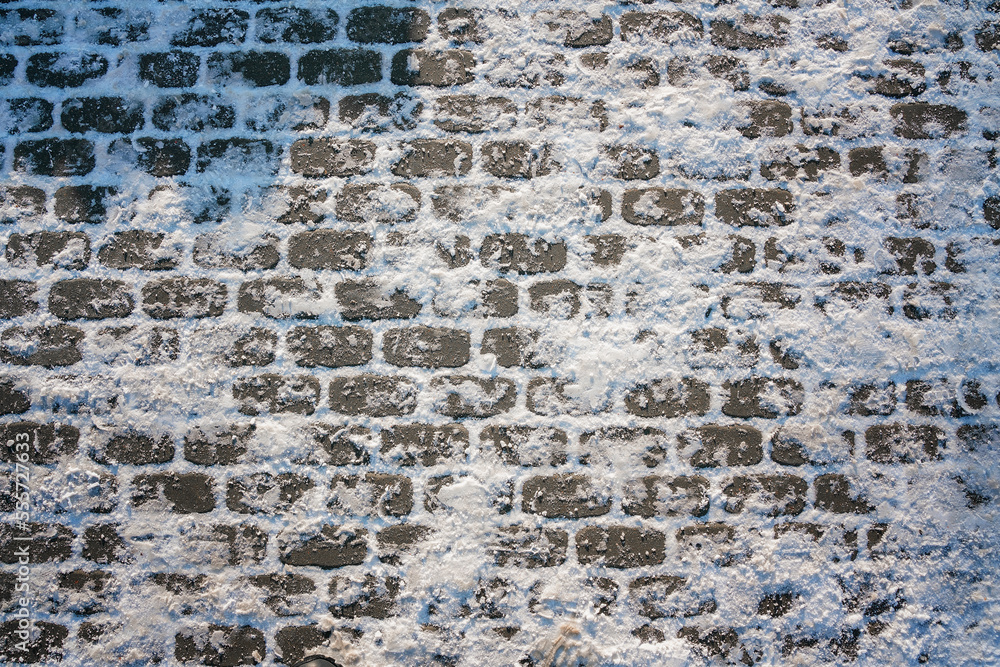 Stone urban pavement is covered with frosty snow and ice. Winter ...