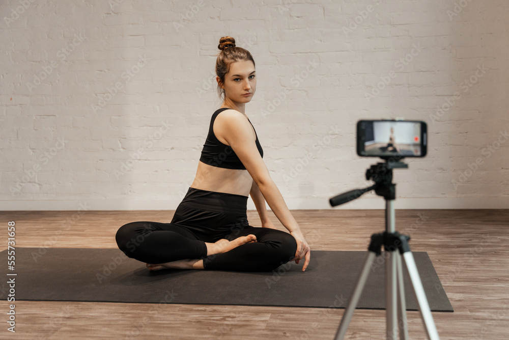 fitness woman make stretching exercises in front camera on tripod at ...