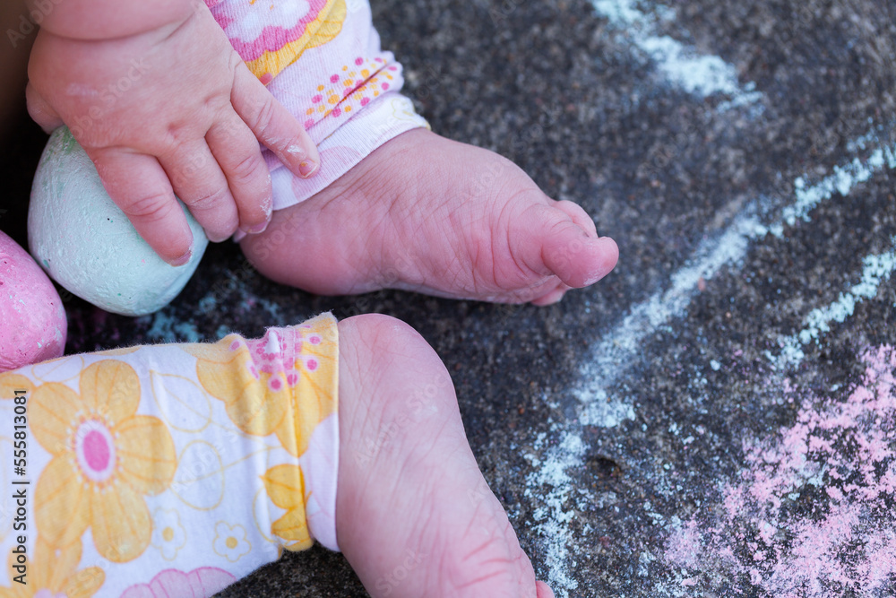 Chubby seven month old baby feet with chalk drawings on concrete ...