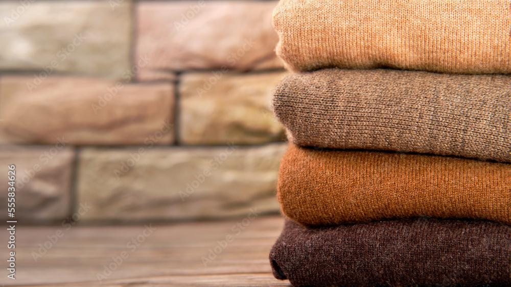 stack of cashmere sweaters in different shades of brown on a brick wall ...