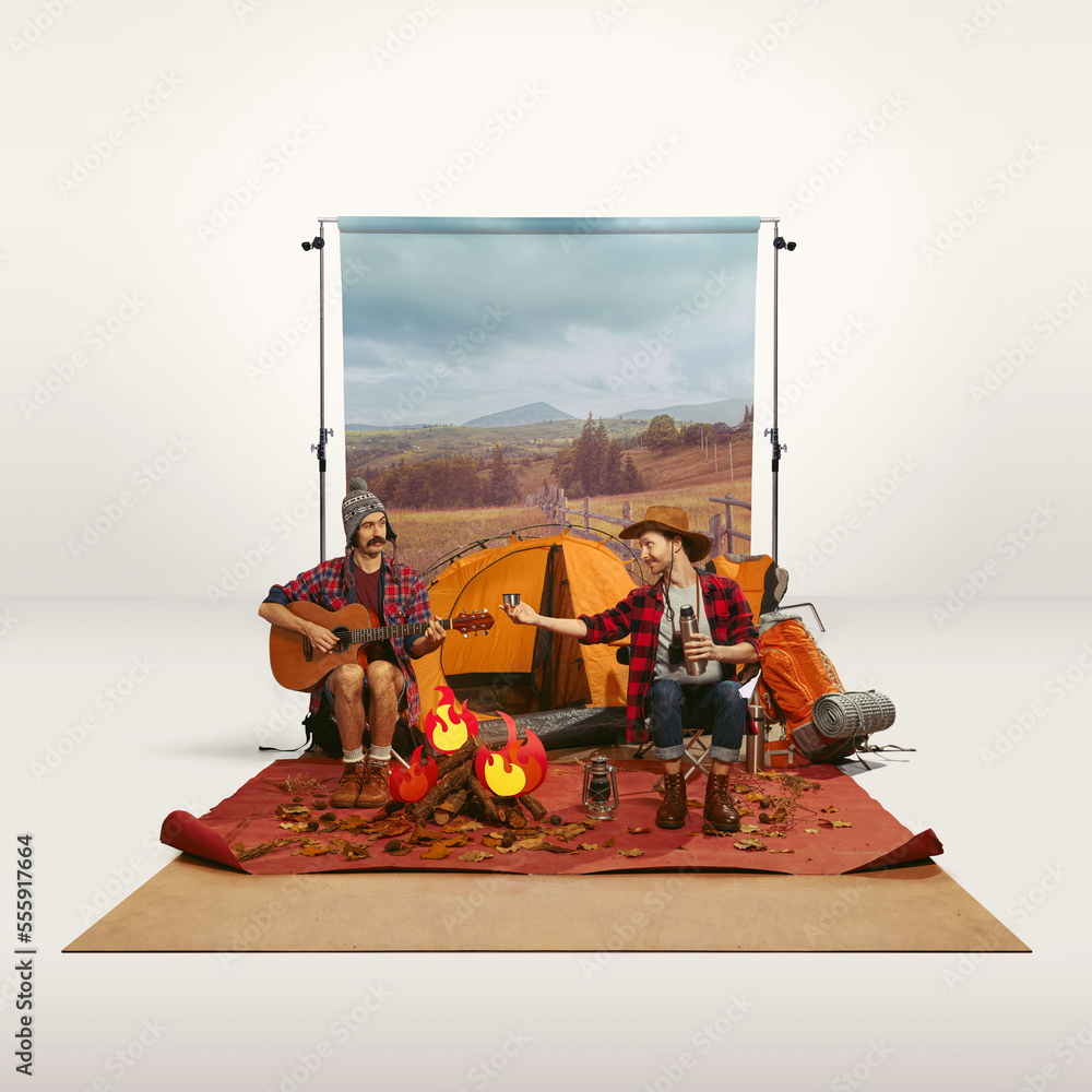 Two mates, men recreating camping activity over grey background with ...