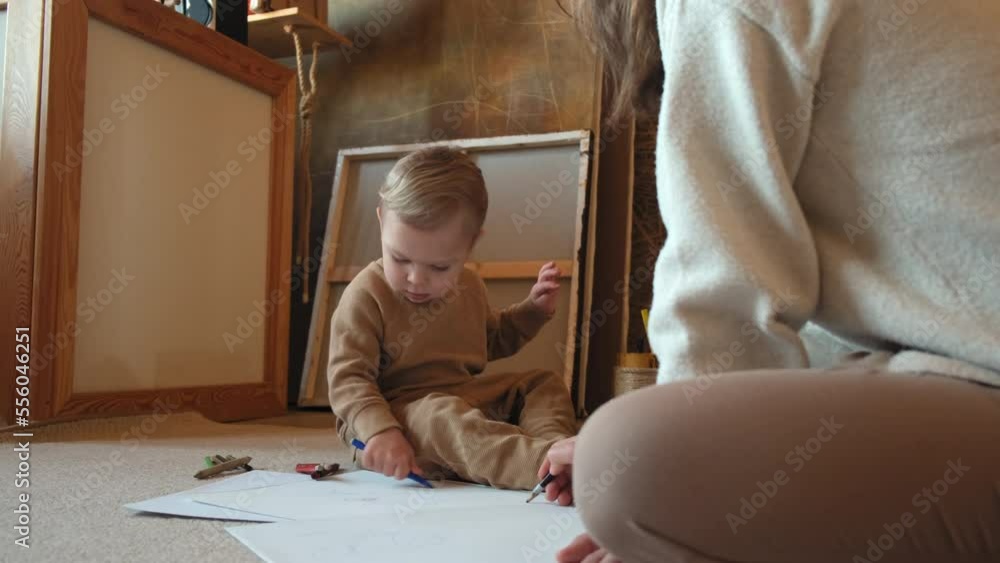 mom is playing with a baby in an art workshop. mom is fooling around ...