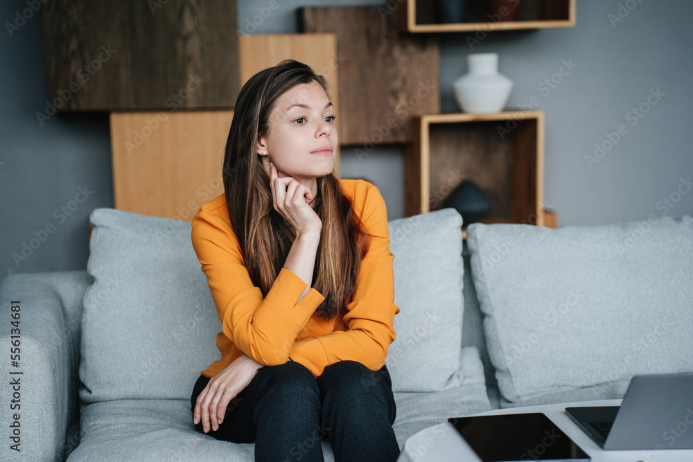 Frustrated brunette hispanic woman in orange blouse sitting on cozy ...