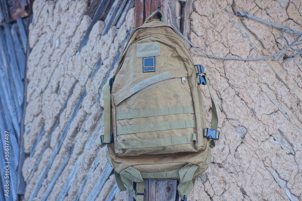 one big green tactical army backpack hanging on a brown clay wall in ...