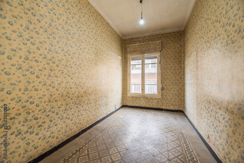 Bedroom with walls covered in old dirty wallpaper, worn hydraulic ...