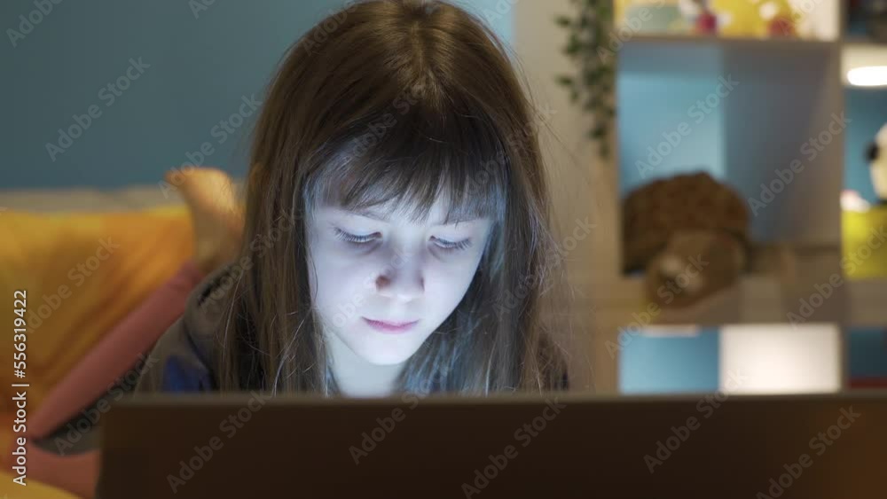 Little girl looking at laptop in night room. Happy little girl. The ...