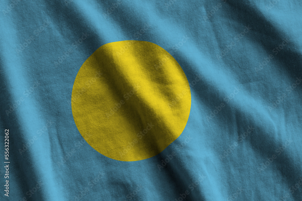 Palau flag with big folds waving close up under the studio light ...
