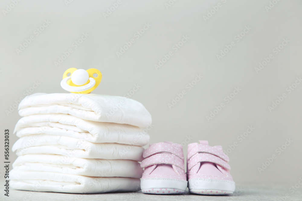 Baby diapers with pacifier and pair of shoes on grey background Stock ...