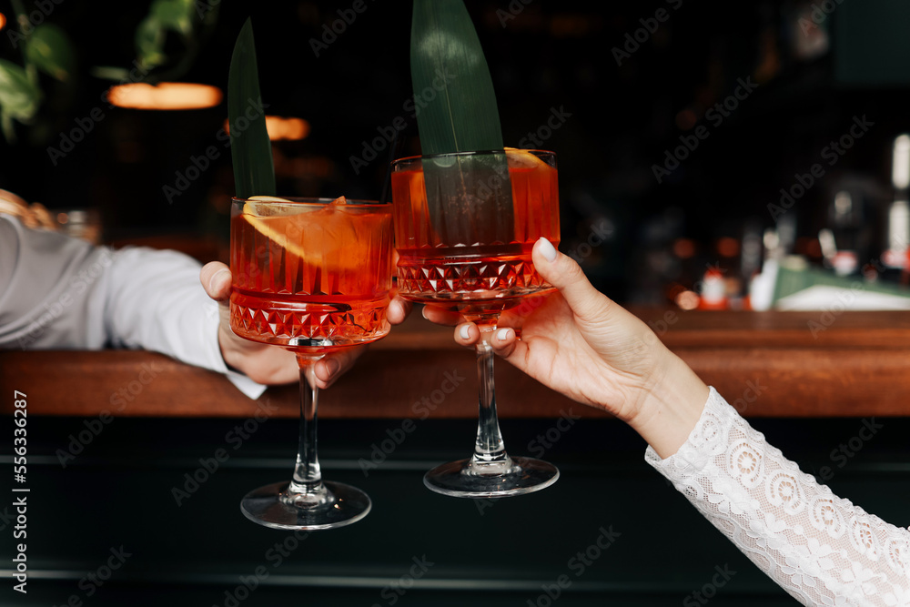 hands of woman and man are clinking, cheers with glasses of Spritz ...