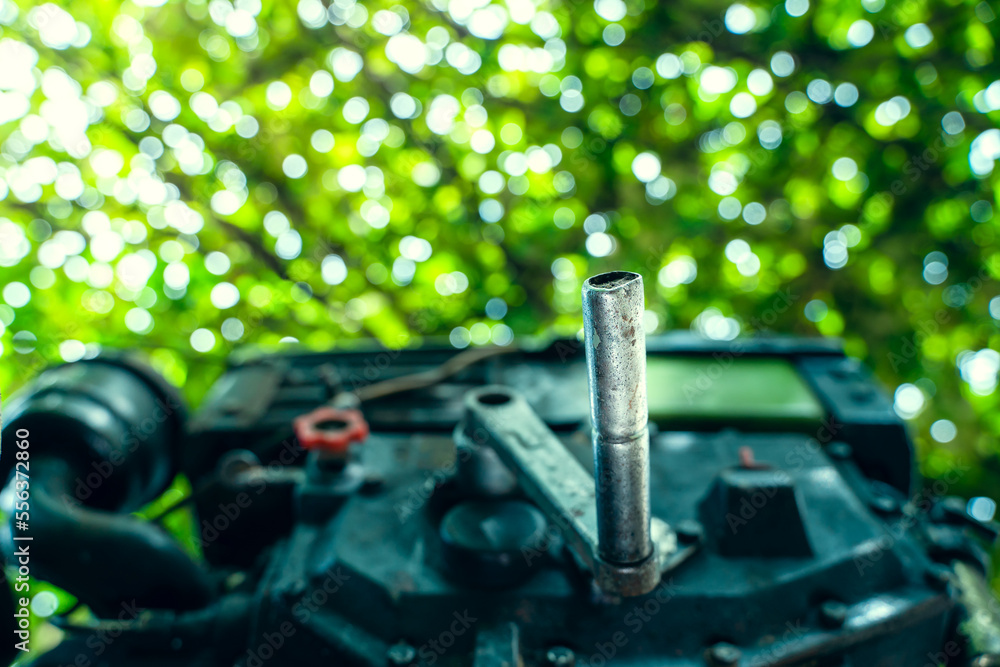 A crooked starter is inserted into the engine of a walk-behind tractor ...