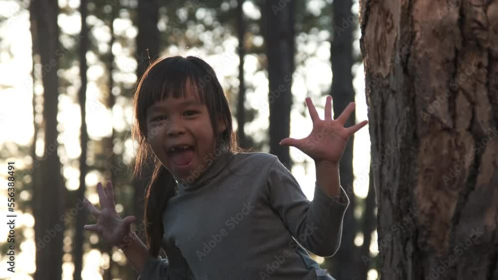 Funny little girl peeking out from behind tree in winter park. Cute ...