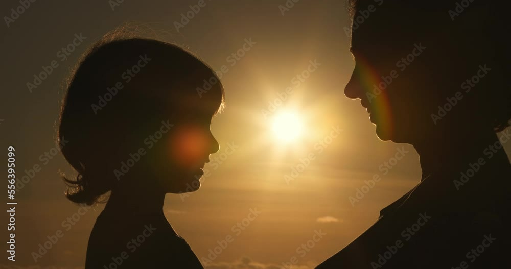 mother and little son silhouette at sunset, sun flare shot closeup ...
