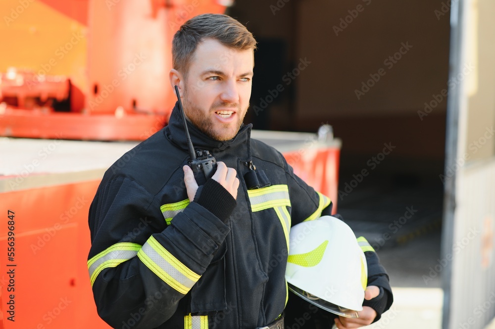 Fireman in a protective uniform standing next to a fire truck and ...