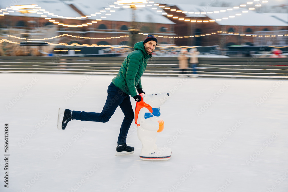 Young male begginer learns skating with help of special figure, leans ...