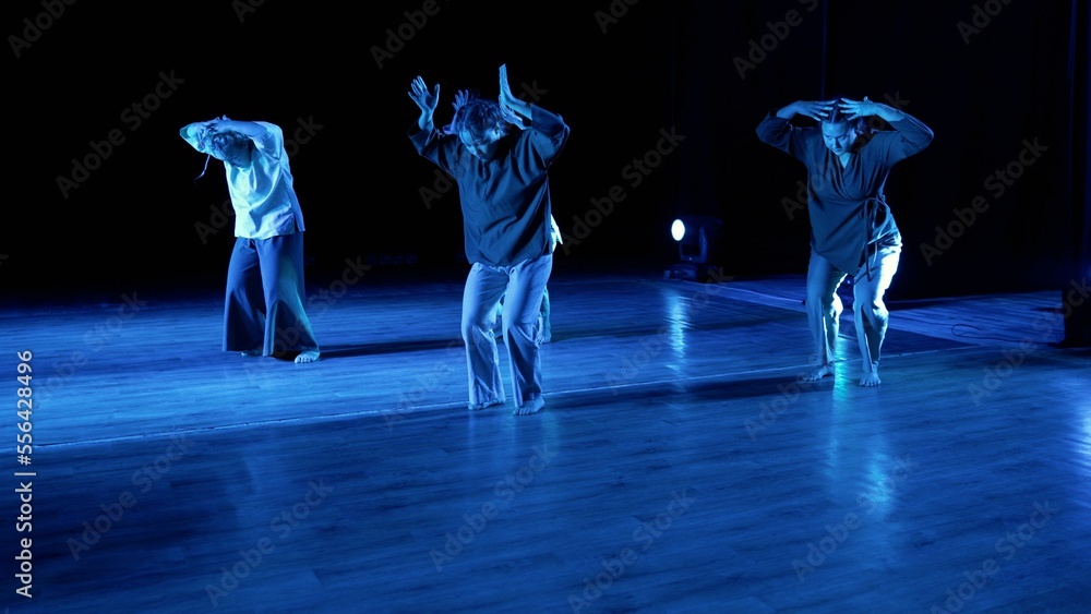 A group of dancers perform on stage. A group of artists are rehearsing ...