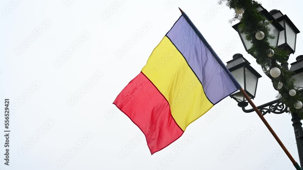 The national flag of Romania on flagpole. Blue, yellow and red colors ...