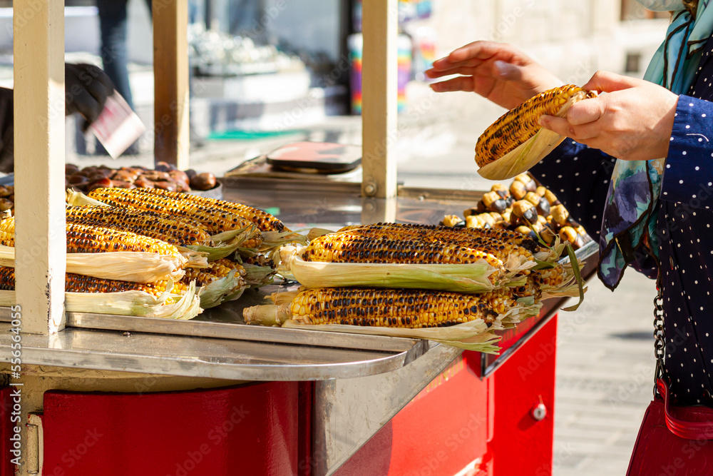a woman is purchasing charbroiled fresh corn on the cob from a street ...