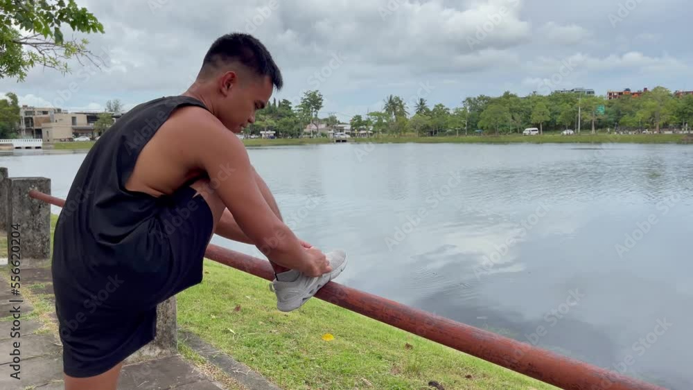 Filipino man on sports clothes getting ready for workout by park lake ...