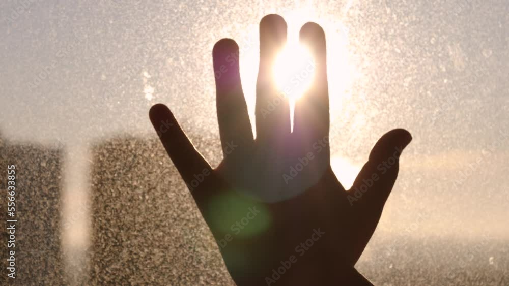 Palm of helping hand on glass of window in apartment of house. Sun rays ...