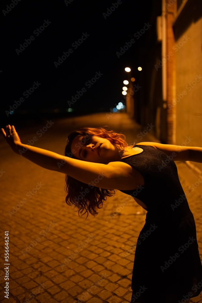 Elegant female dancer at night. Woman in black dress standing in ballet ...