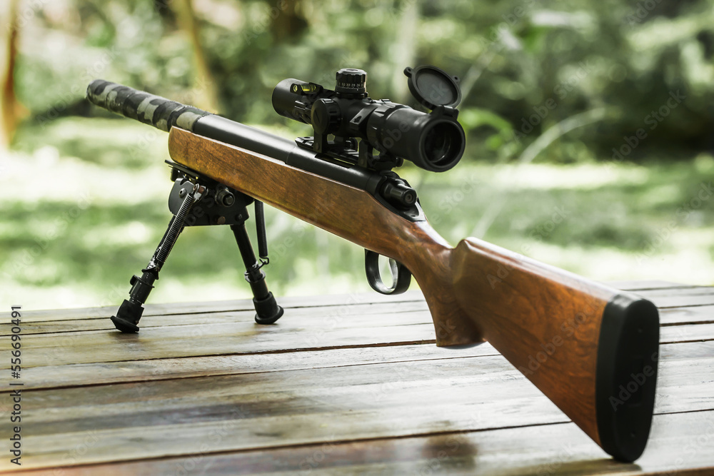 Wooden bolt action short sniper rifle with scope and bipod standing on ...